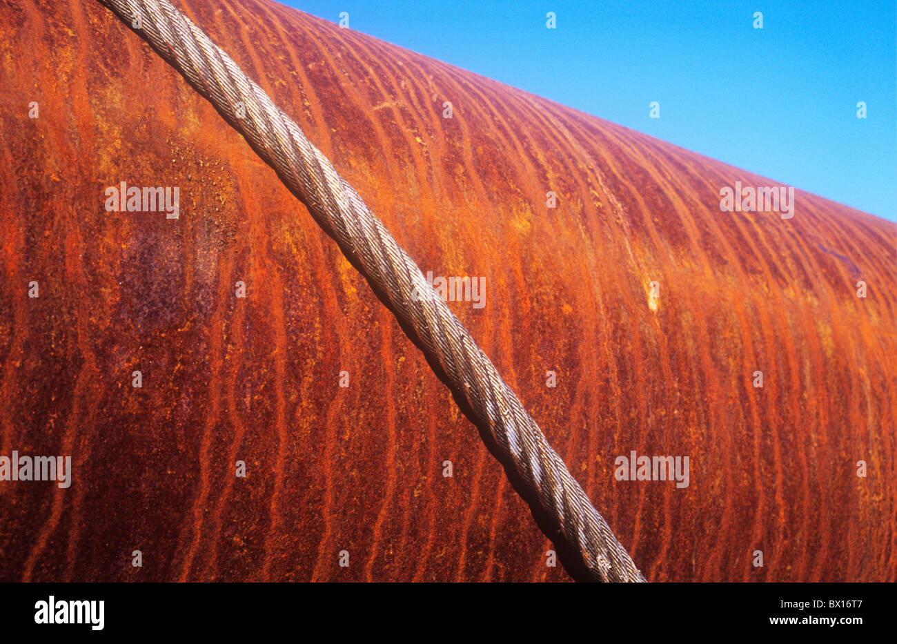 Large metal tube with water-stained rusty surface and thick steel cable ...