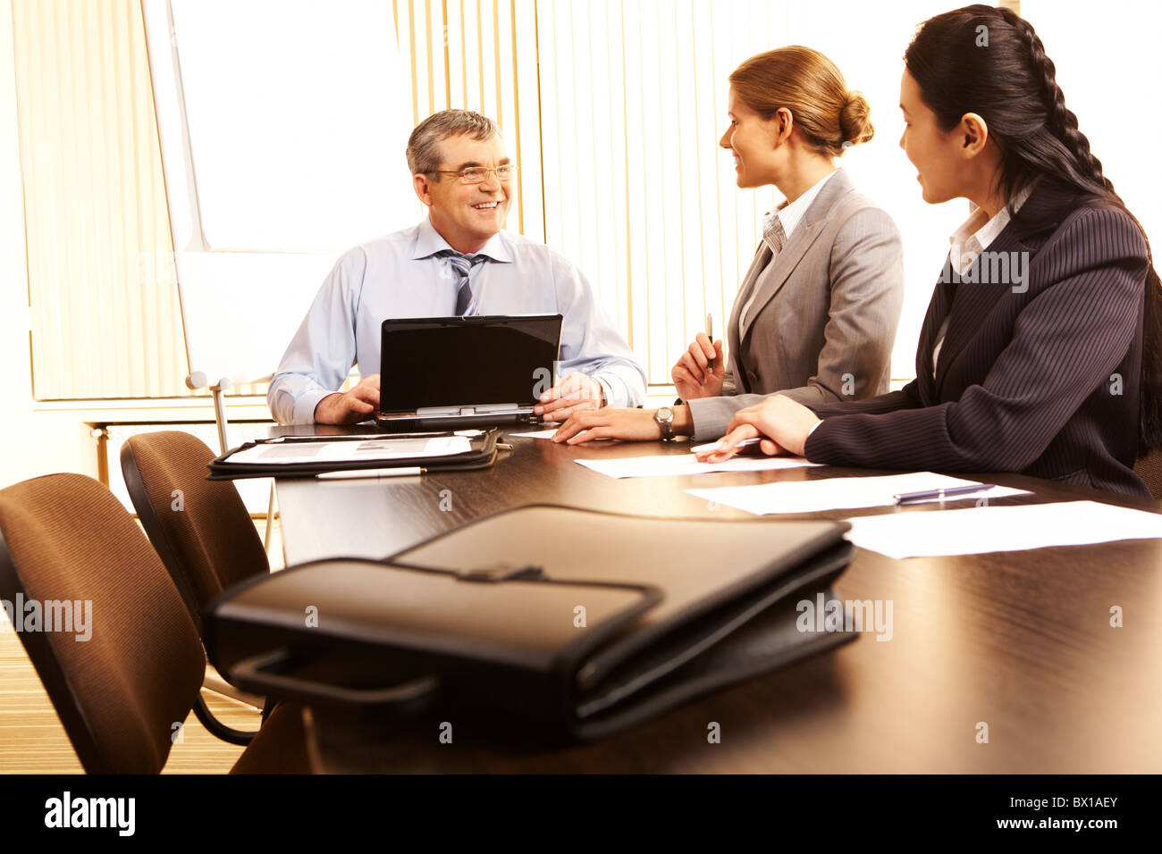 Photo of friendly business group sitting at the desk in the far end of ...