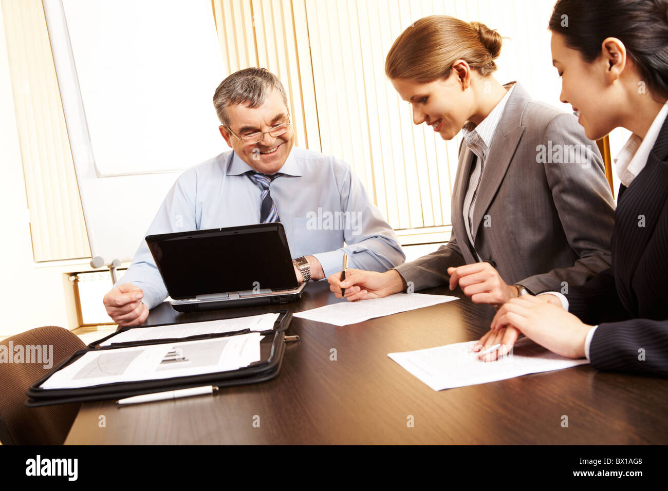 Photo of friendly business group sitting at the desk in the office and ...