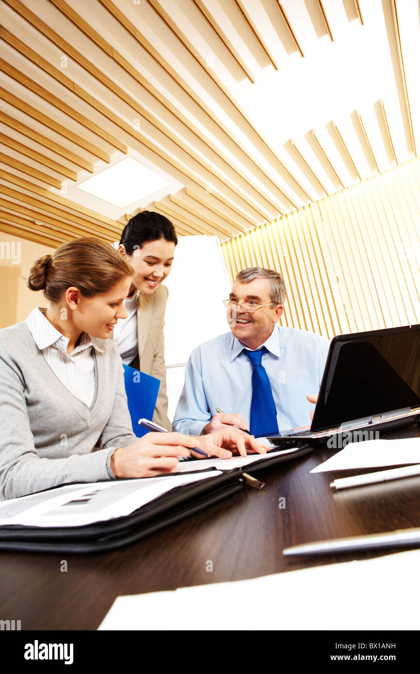 Photo of friendly business group sitting at the desk in the office and ...