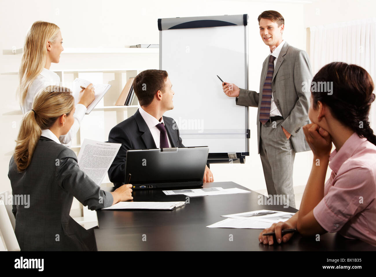 Image of smart business people looking at their leader while he ...