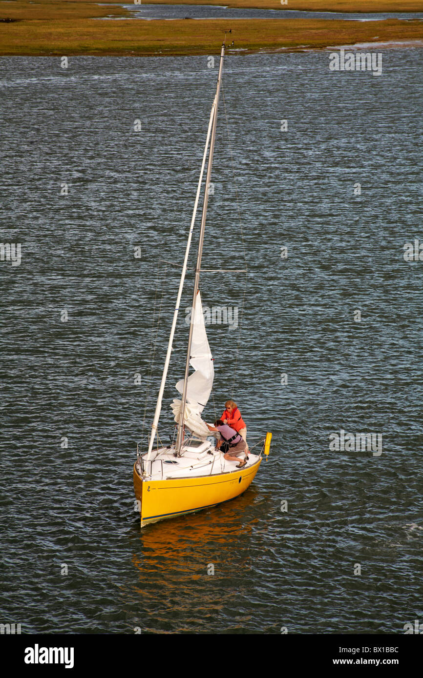 Couple taking down the sails on yacht as they approach Lymington ...