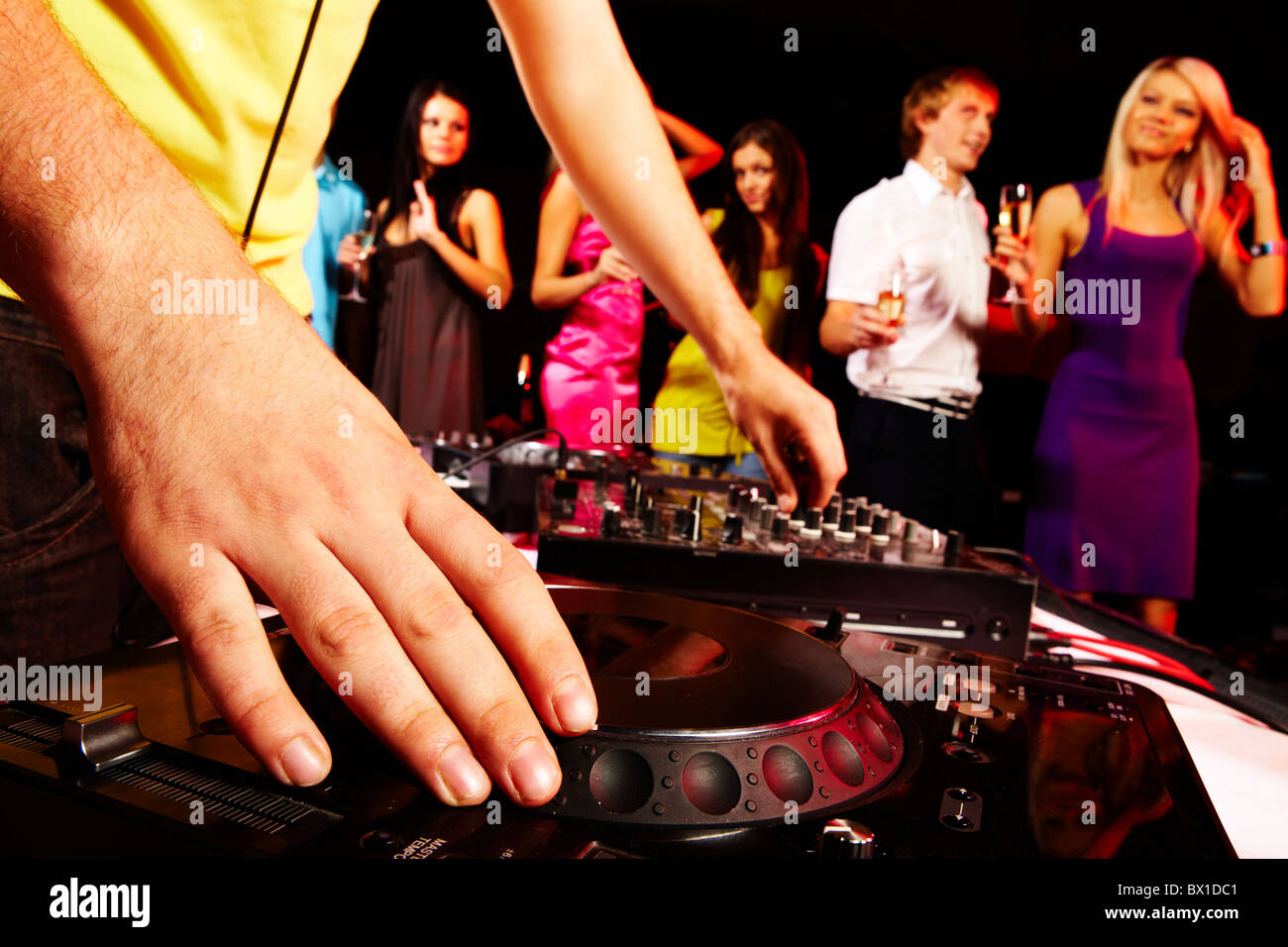 Close-up of human hand spinning turntable with group of dancers on ...