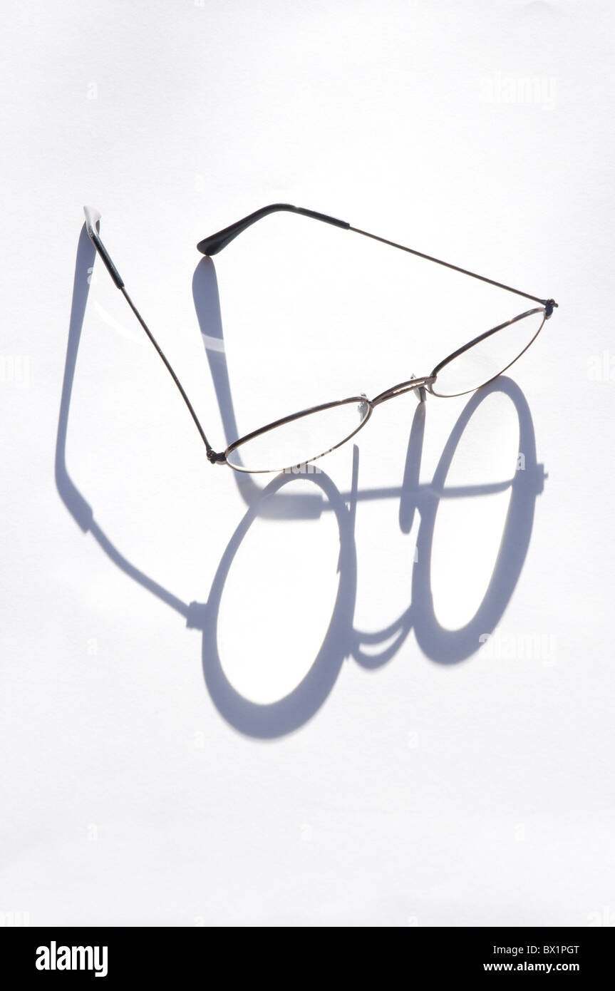 Black framed reading glasses casting shadow Stock Photo - Alamy