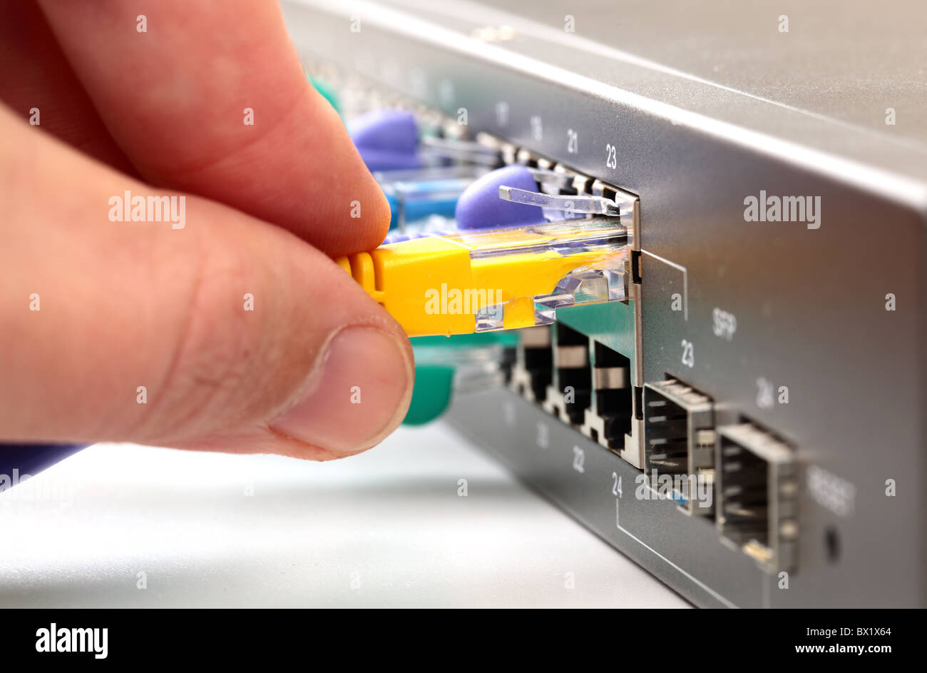 Hand connecting yellow internet cable to hub Stock Photo - Alamy