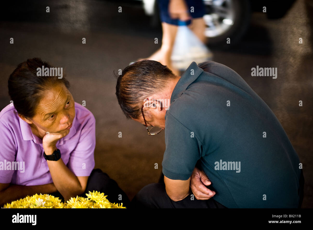 Two tired flower sellers at the night market in Chiang Mai in Thailand ...