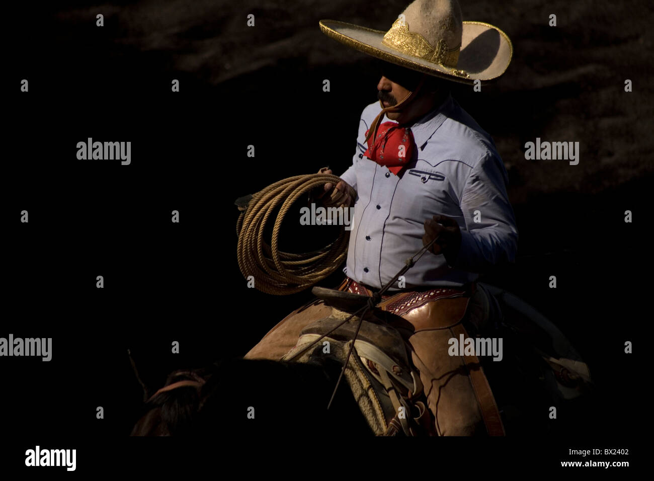 A Mexican Charro holds his lasso as he rides a horse during a charreria ...