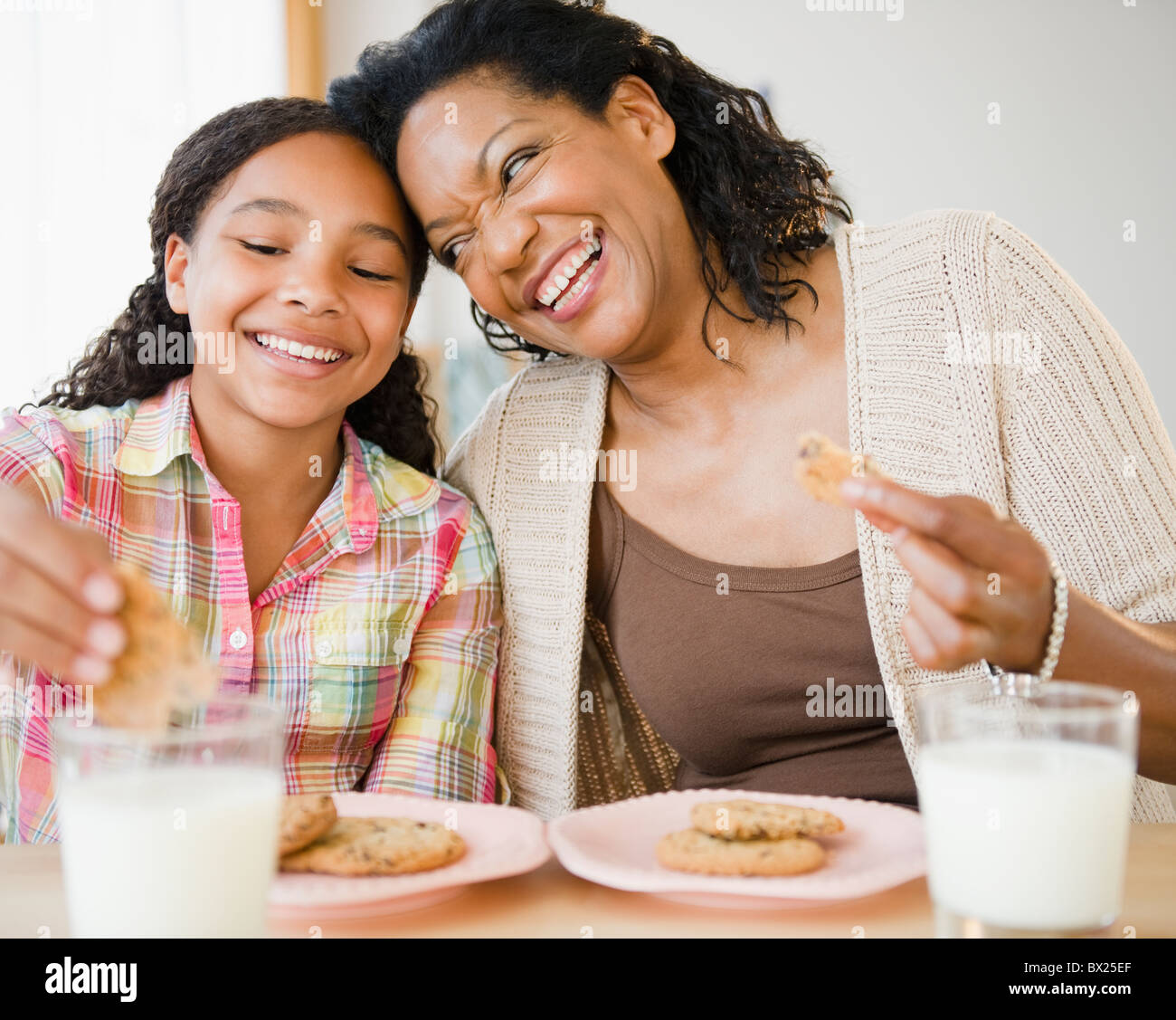 Mother and daughter eating cookies and milk together Stock Photo - Alamy