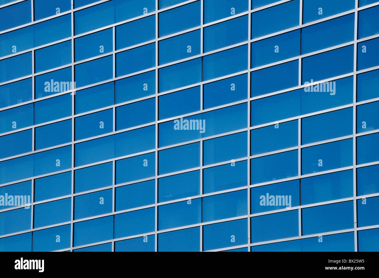 Exterior windows of a modern commercial office building reflecting blue ...