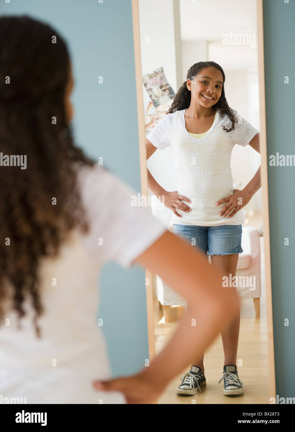 Mixed race girl checking reflection in mirror Stock Photo - Alamy
