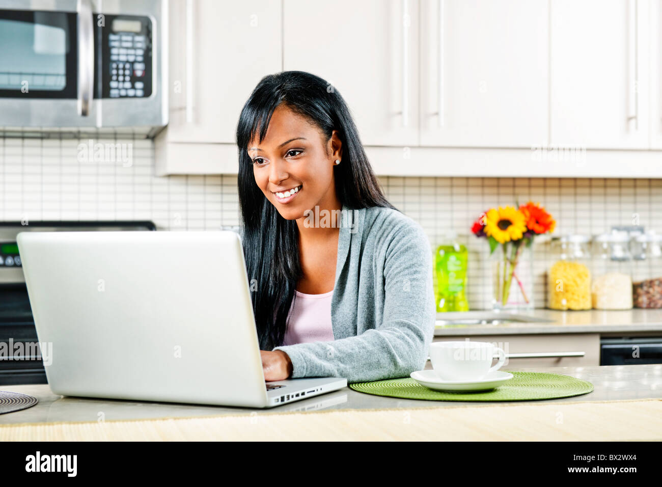 Smiling black woman using computer in modern kitchen interior Stock ...