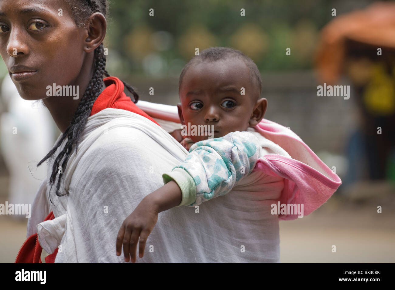 Woman with child on her back in the street Stock Photo - Alamy