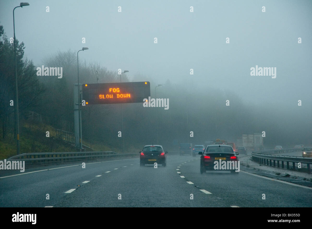 'Fog Slow Down' - motorway warning sign. Drivers viewpoint with cars ...