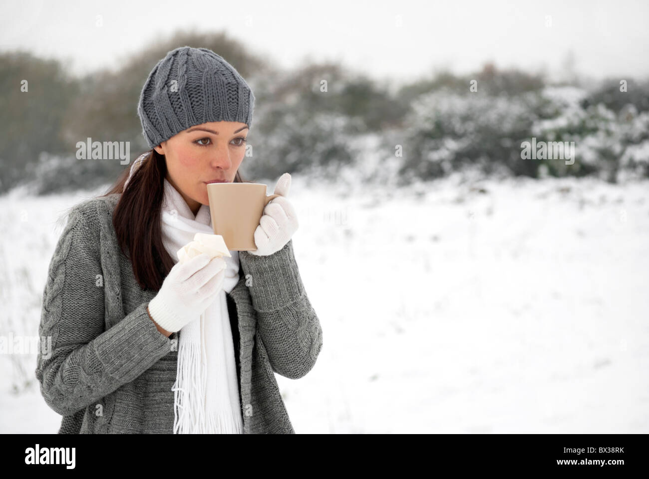 Cold woman with hot drink outside holding tissue Stock Photo - Alamy