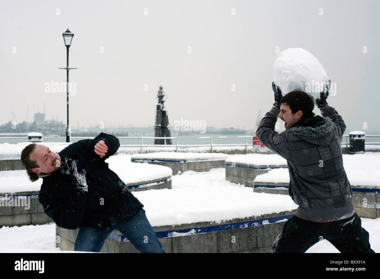 two young men play with a giant snowball during snow storm Stock Photo ...
