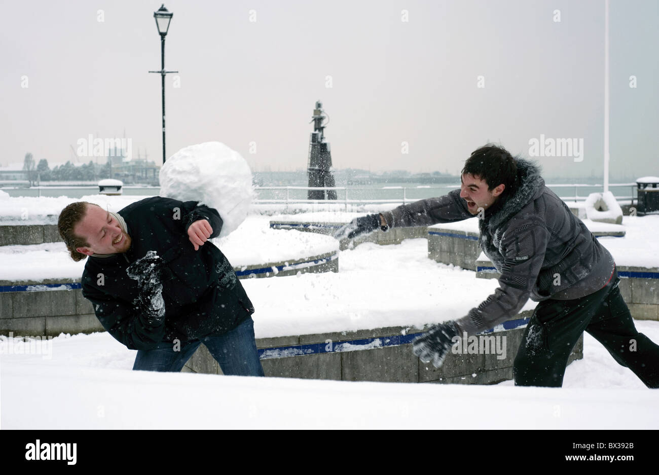 two young men play with a giant snowball during snow storm Stock Photo ...