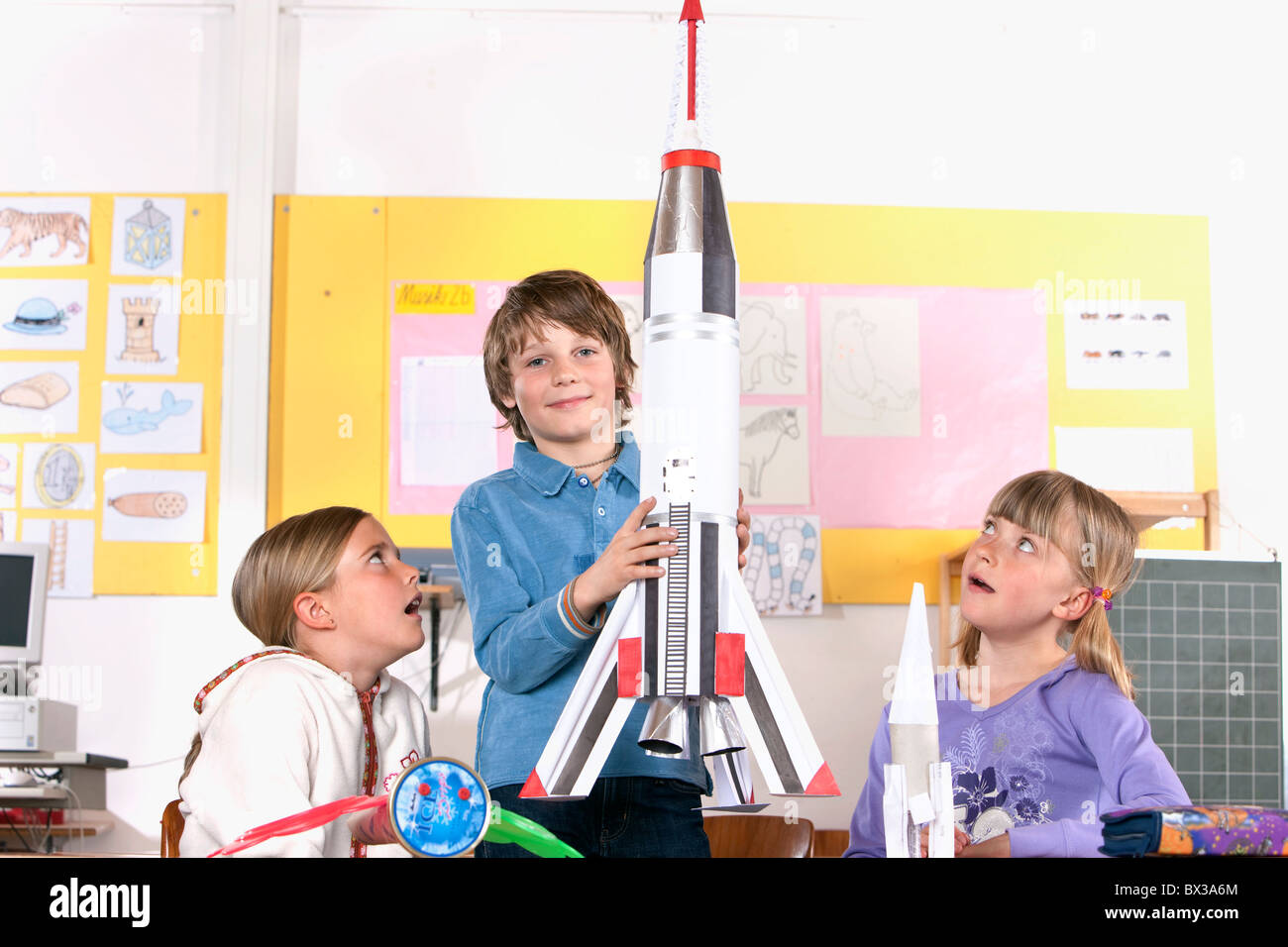 young boy in classroom holding model of rocket Stock Photo - Alamy