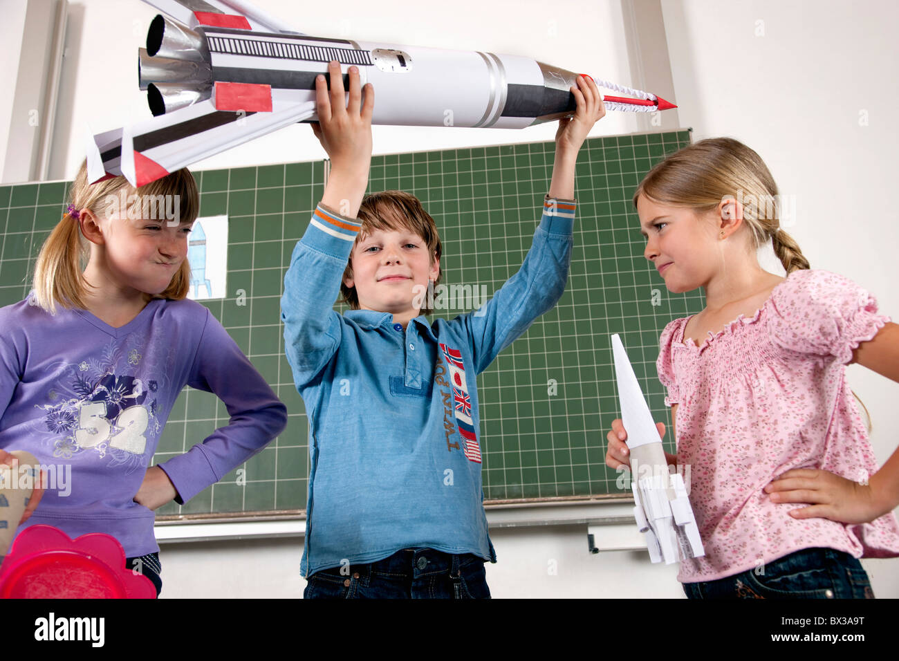 young boy in classroom holding model of rocket Stock Photo - Alamy