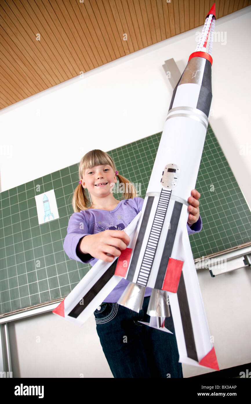 portrait of young girl in classroom holding model of rocket Stock Photo ...