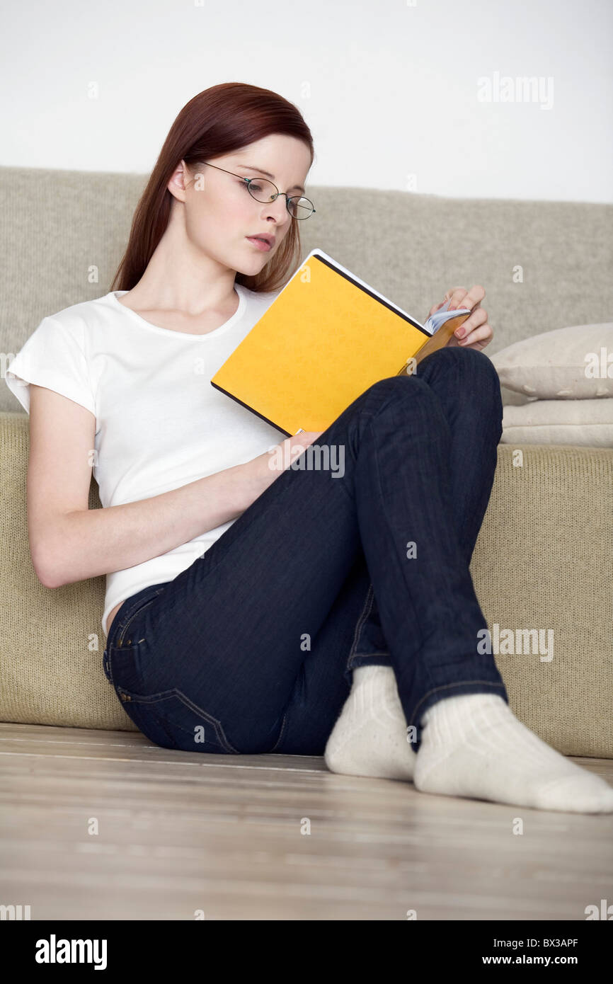 young woman sitting on floor reading book Stock Photo - Alamy