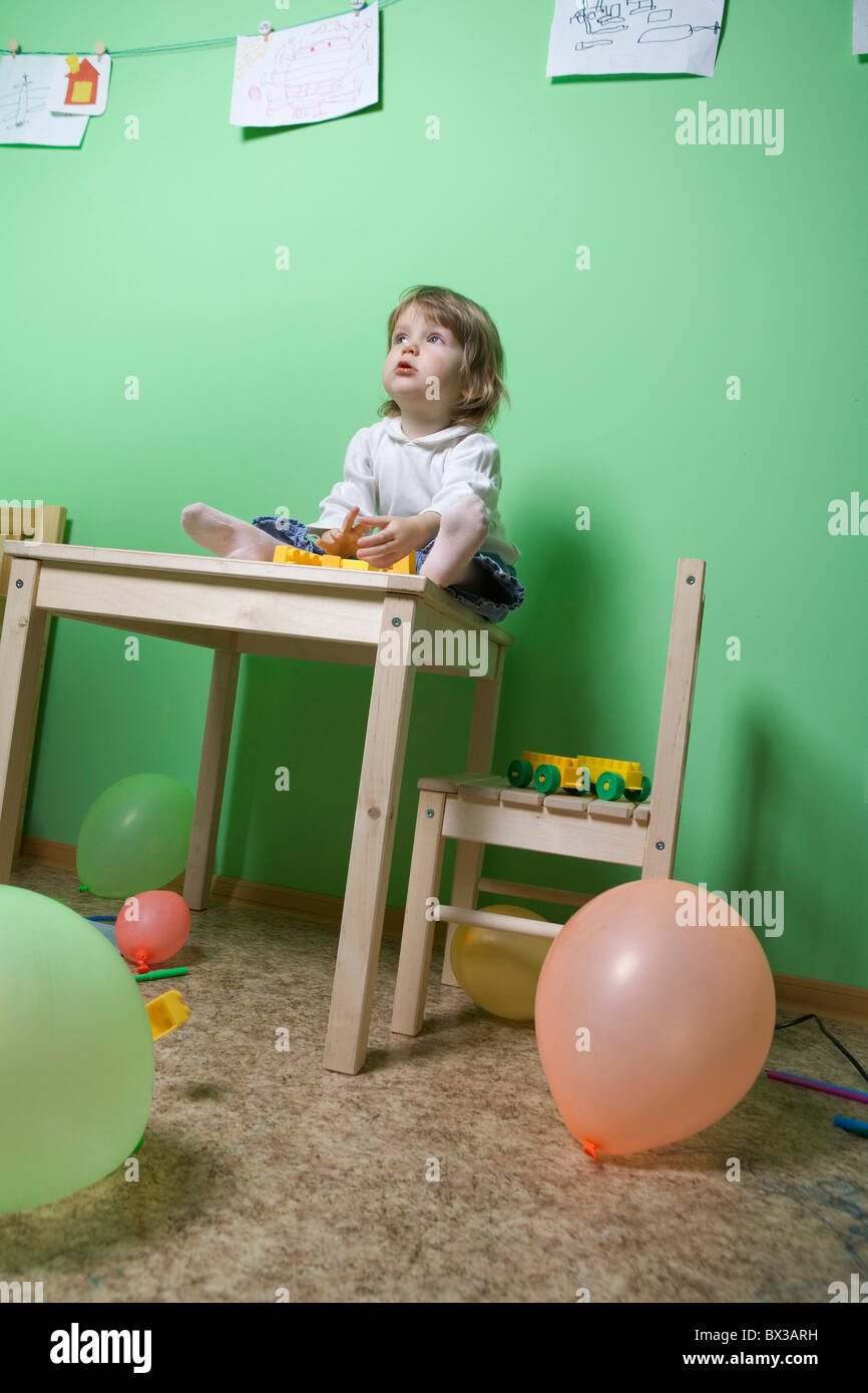 young girl sitting on table in children´s room Stock Photo - Alamy