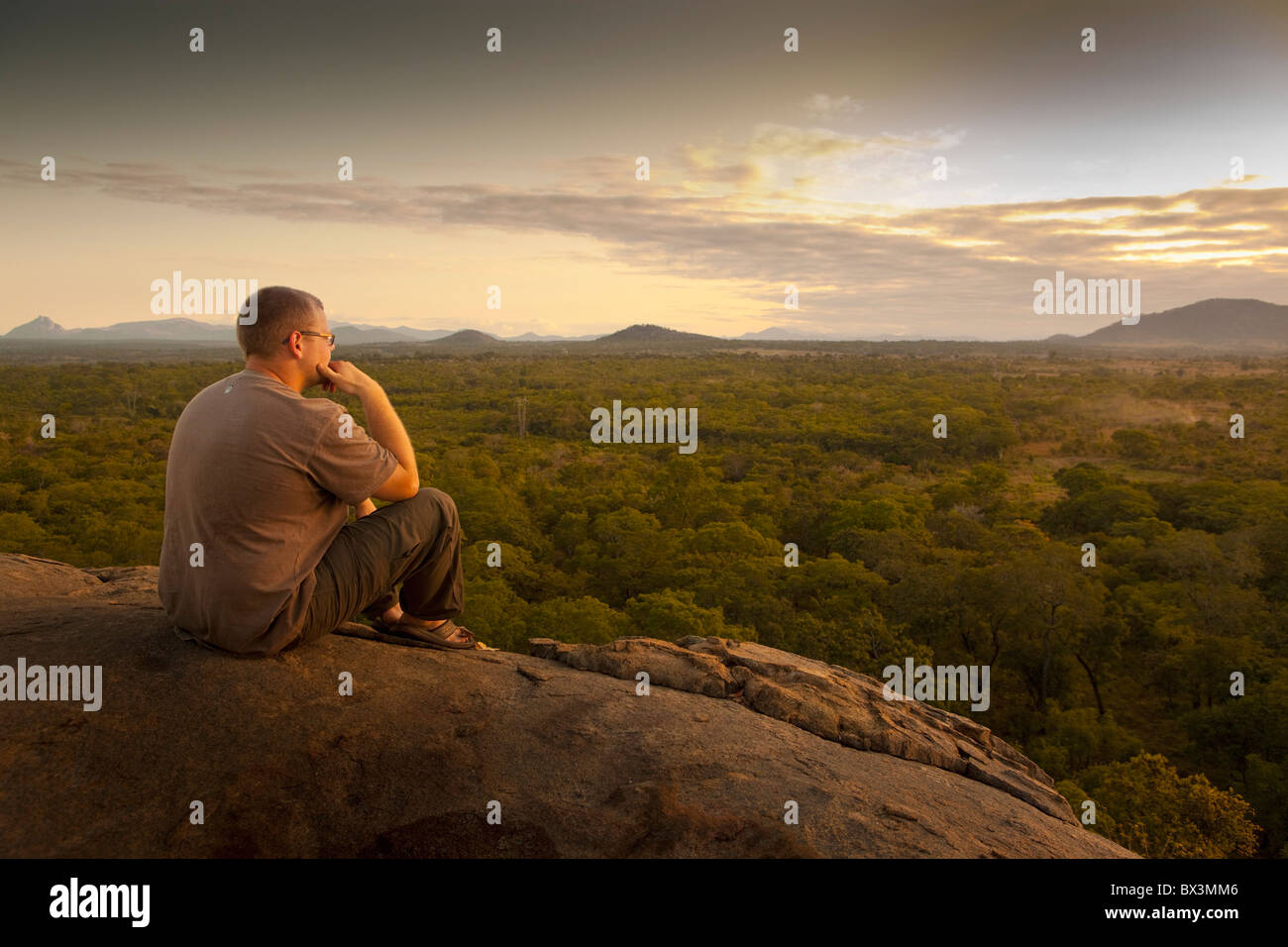 Male sitting on a rock looking back hi-res stock photography and images ...