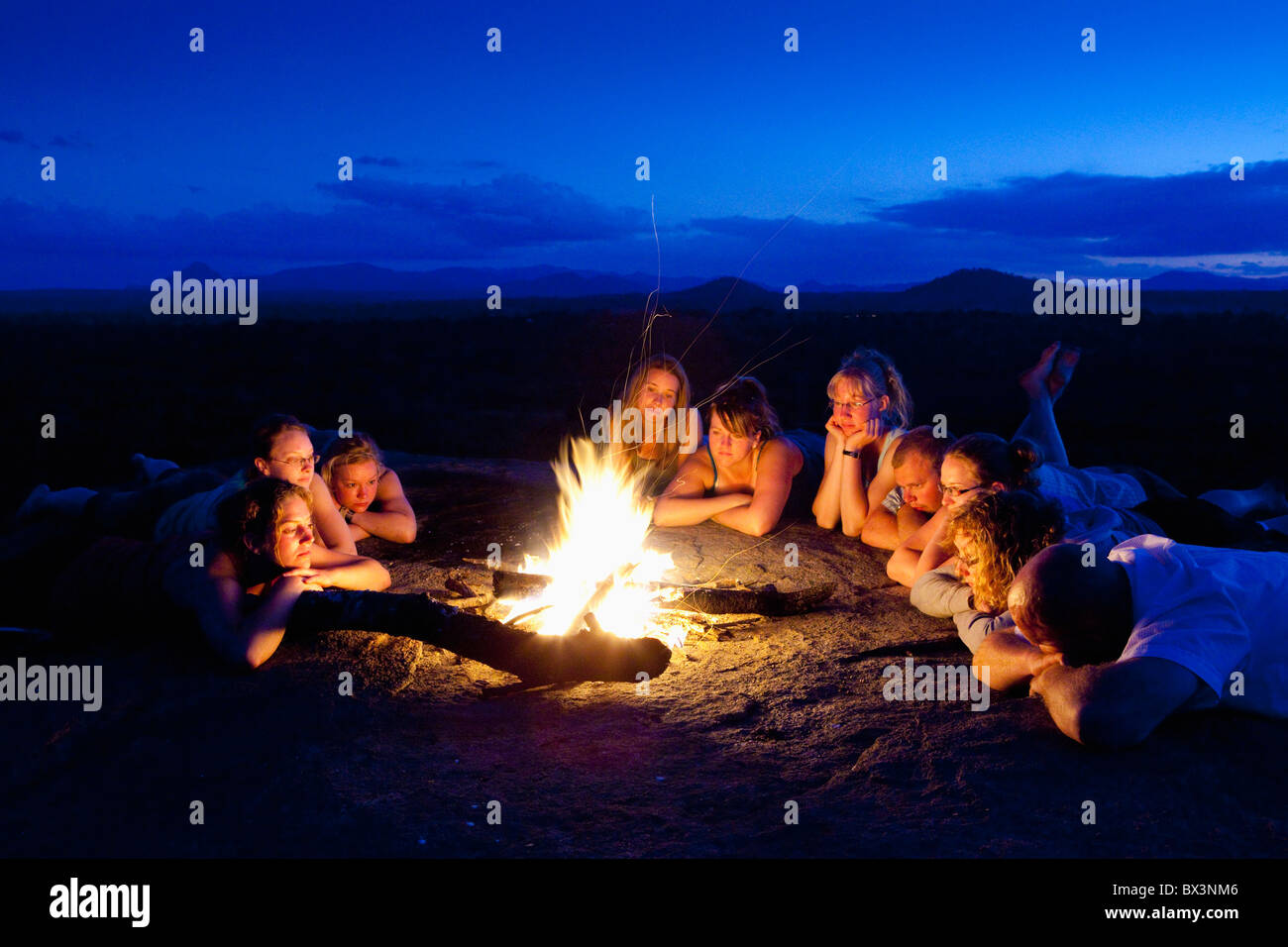 A Group Of People Laying By A Campfire; Manica, Mozambique, Africa ...