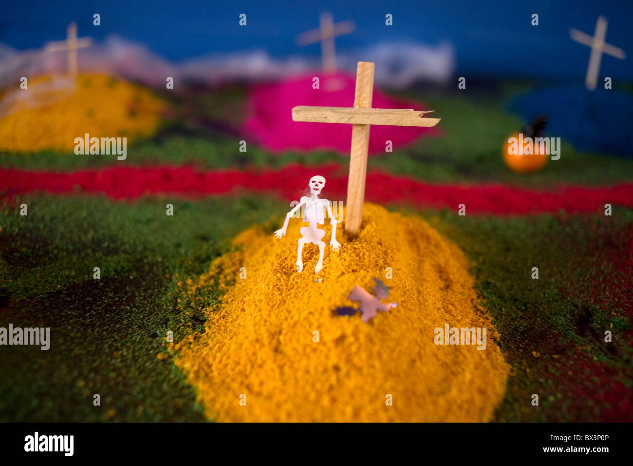 A paper skeleton decorates a tomb made of painted sand as part of an ...