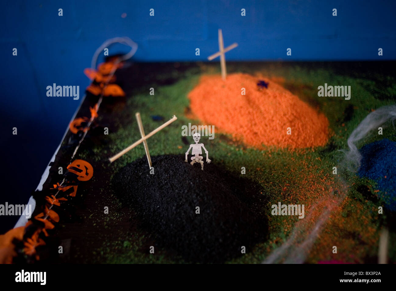 A paper skeleton decorates a tomb made of painted sand as part of an ...