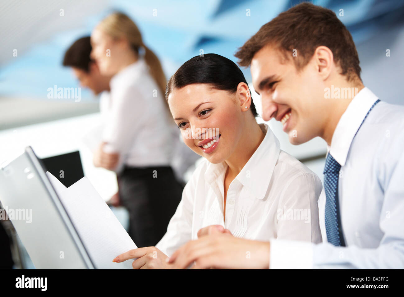 Portrait of executive partners looking at laptop on background of their ...