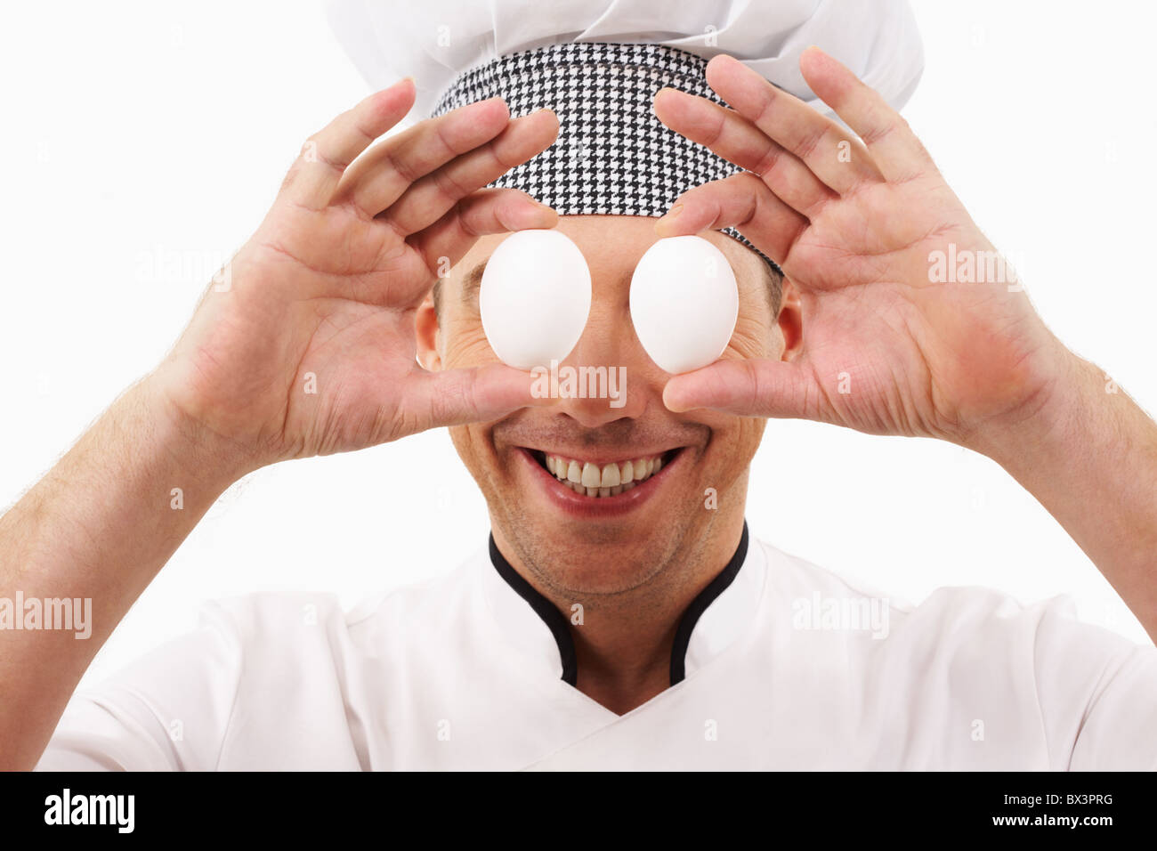 Portrait of handsome man in cook uniform holding two eggs in front of ...