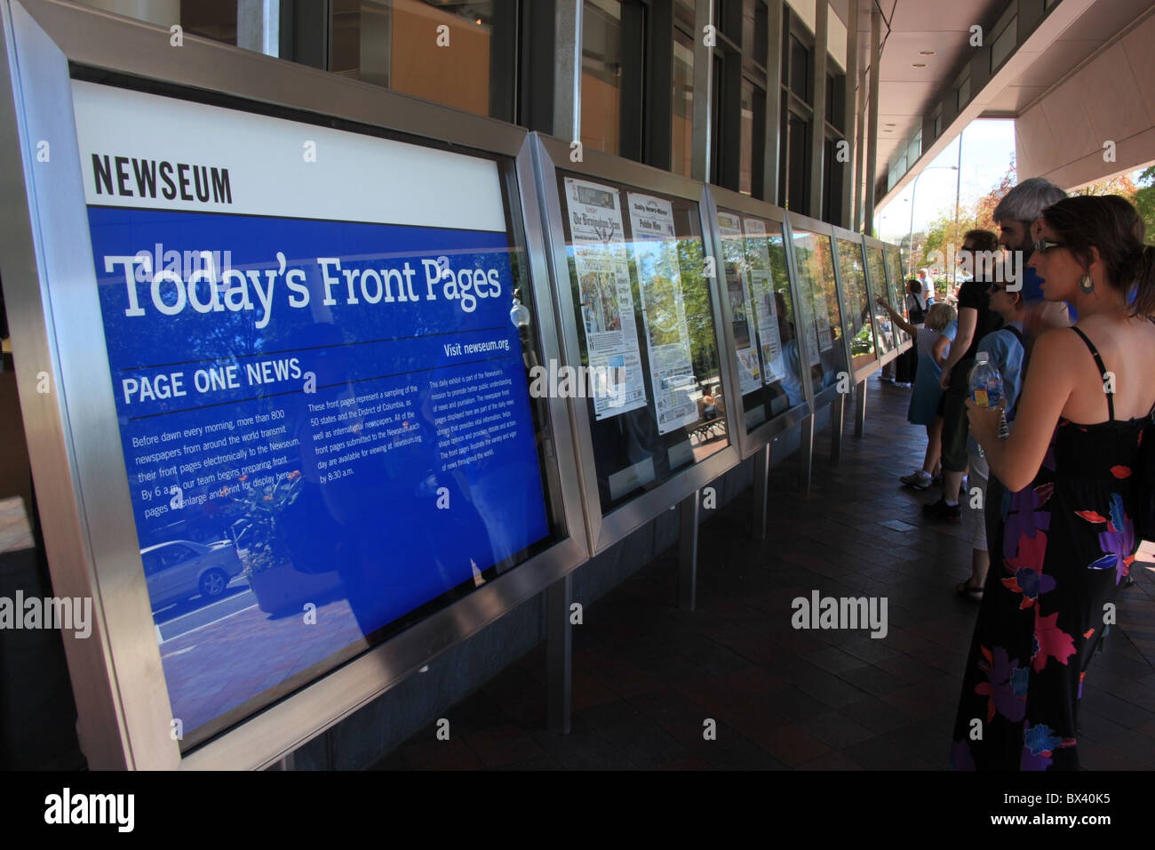 Tourists read Today's Front Pages display at the Newseum in Washington ...