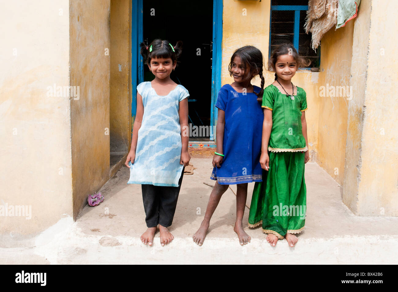 Smiling happy Indian village girls standing in front of their house ...