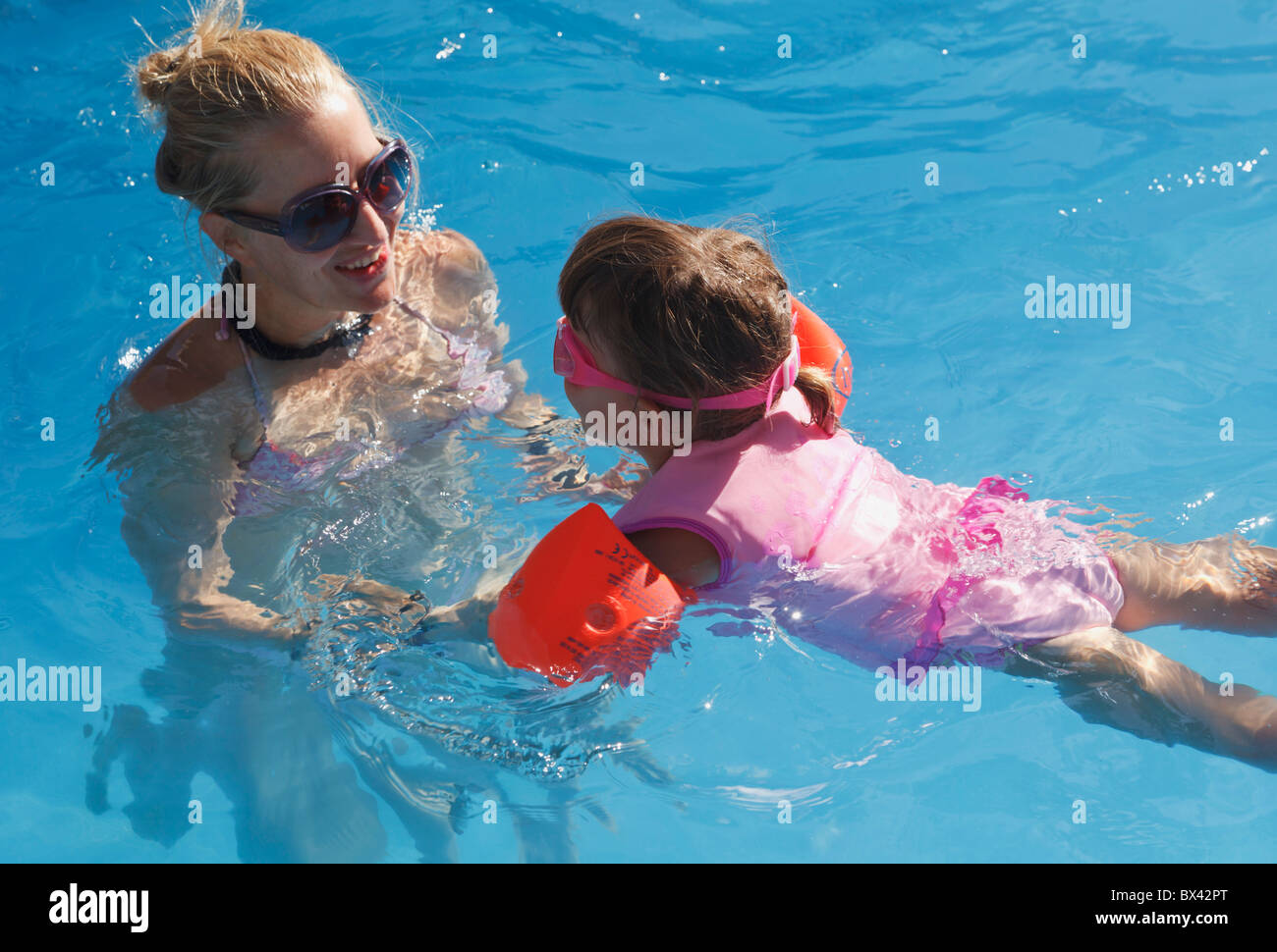 A Young Girl Wearing A Personal Floatation Device Vest And Armbands To ...