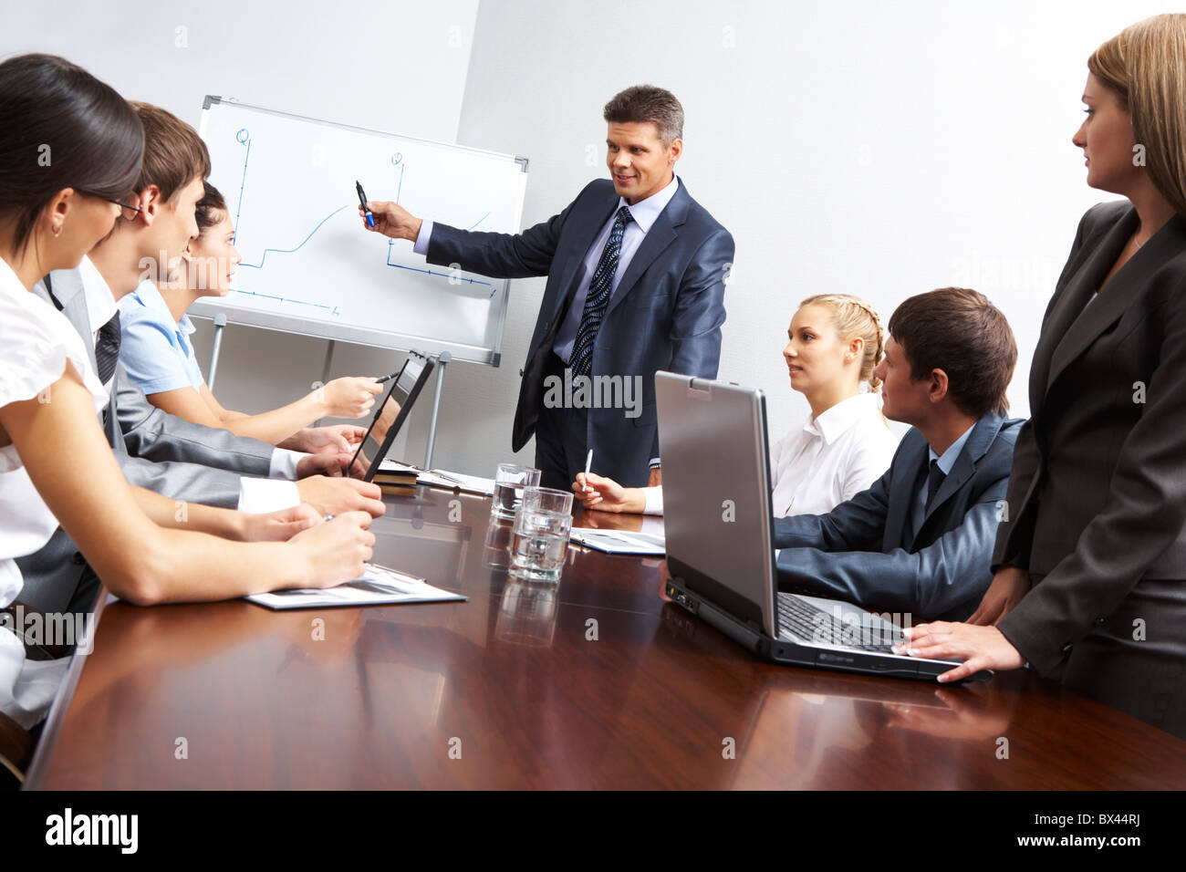 Image of smart business people looking at their leader while he ...