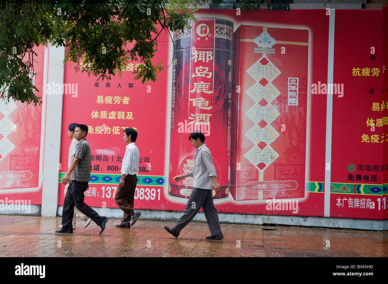 Men walking past a huge advertisement while walking down the street ...