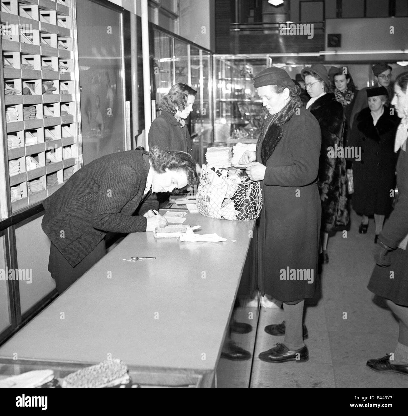 Prague 1948. Shoppers examine Christmas goods offered by Bila Labut ...