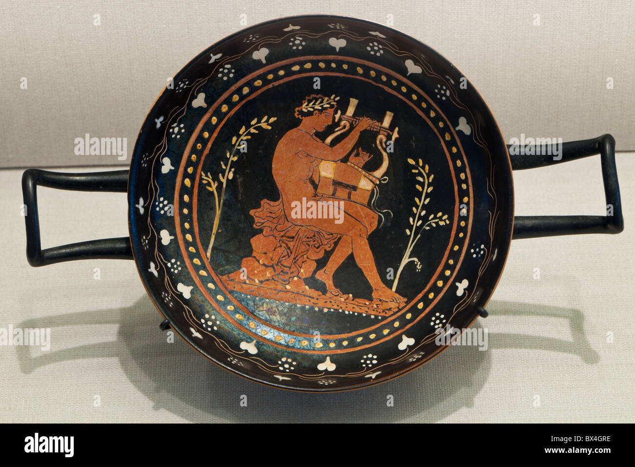Figure of Apollo playing a kithara while seated on a rock. Apulian Red ...