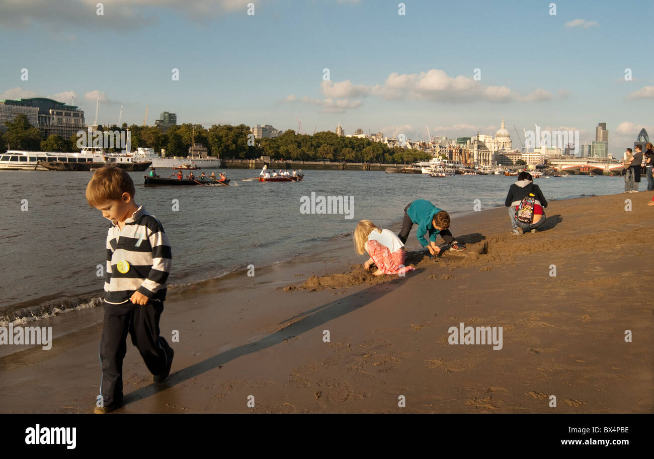 Young children play on the shores of the river Thames in central London ...