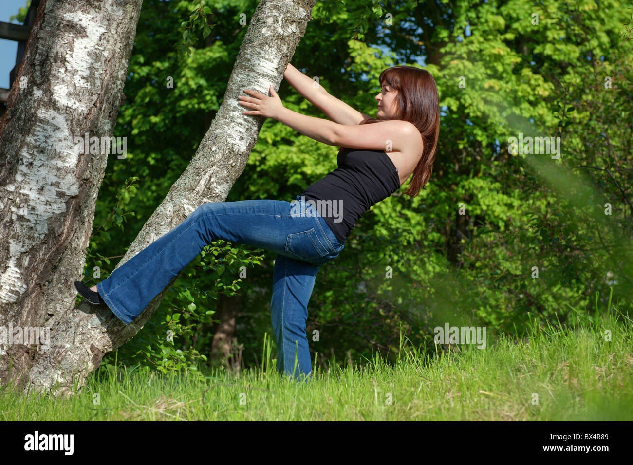 Beauty tomboy trying to get up the tree Stock Photo - Alamy