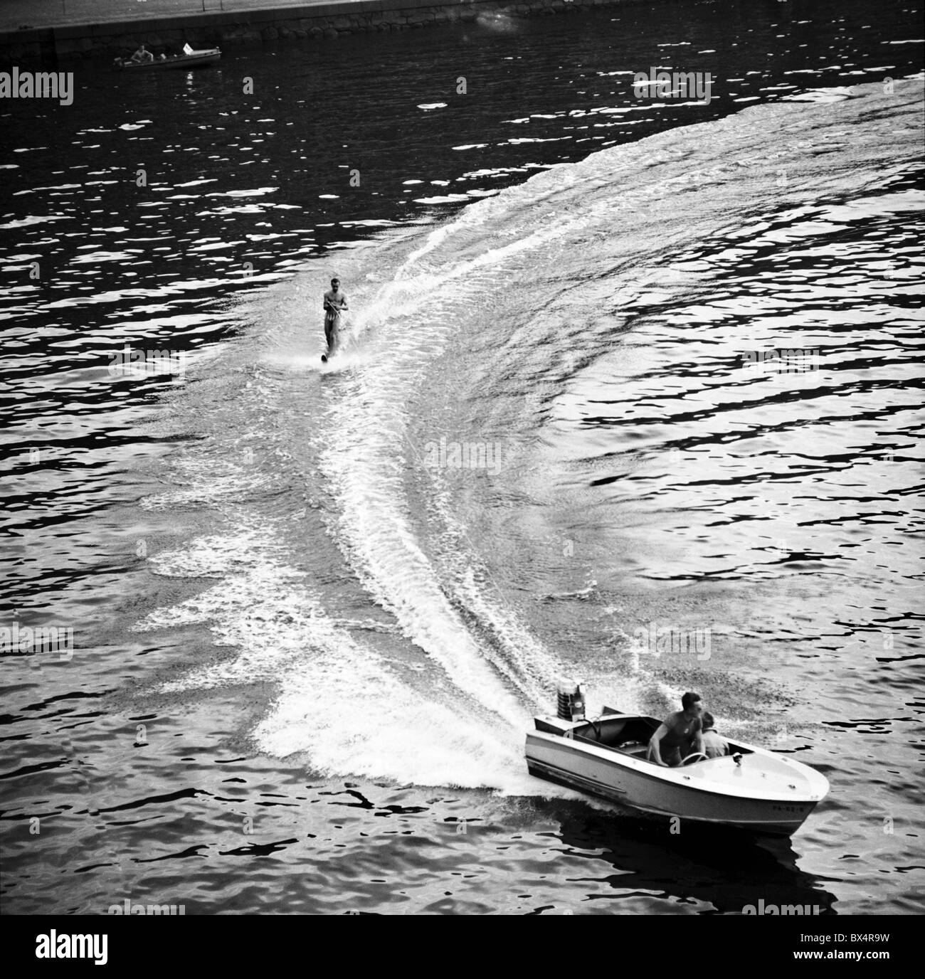 Water skier pulled by motor boat negotiates a curve on Vltava River ...