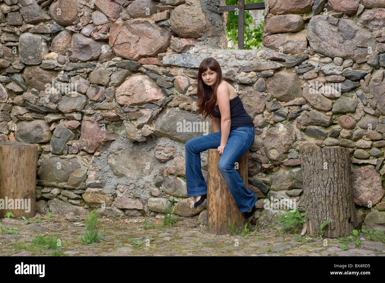Young beautiful woman sitting on the log near old castle ruins Stock ...