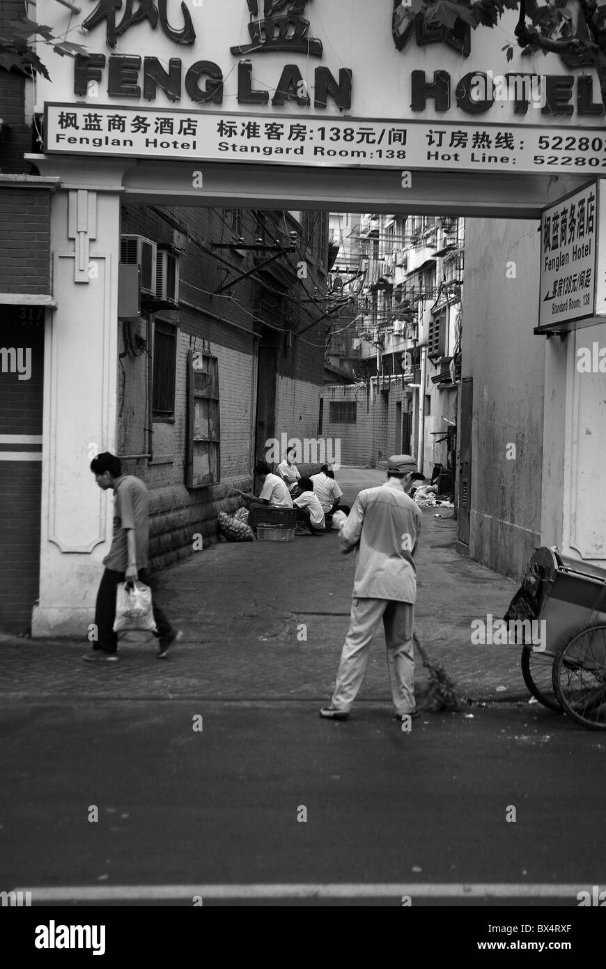 Shanghai - Street cleaner and pedestrian with hunchback at alleyway ...