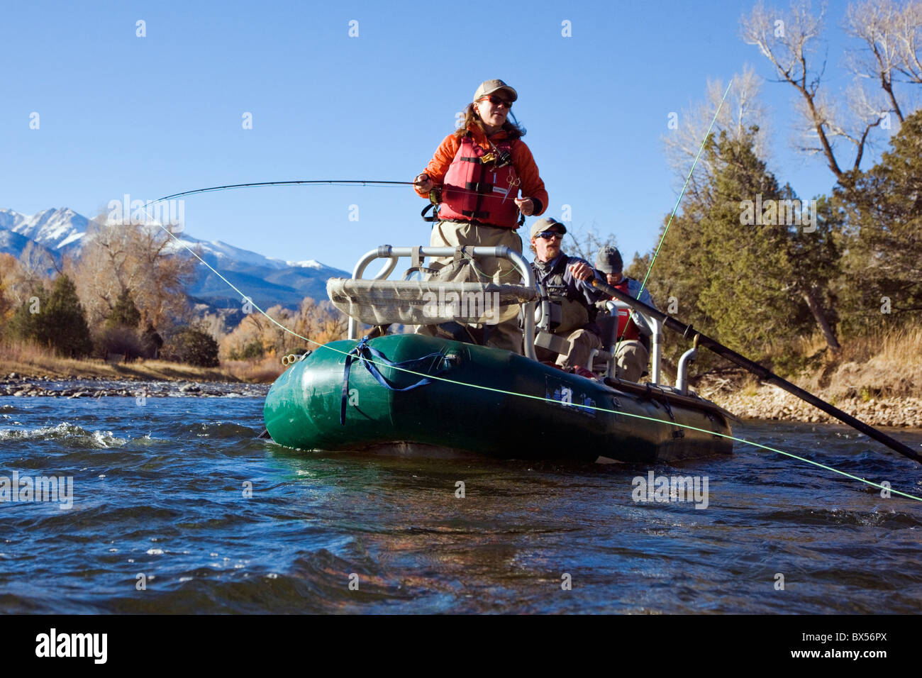 Married couple and professional guide fly fishing from a boat on the ...