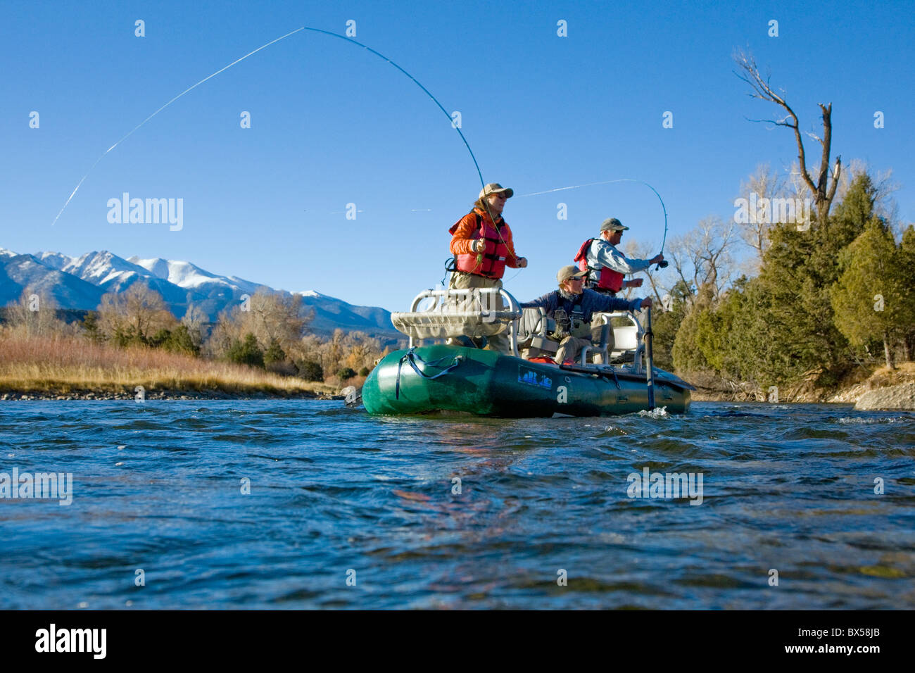 Married couple and professional guide fly fishing from a boat on the ...