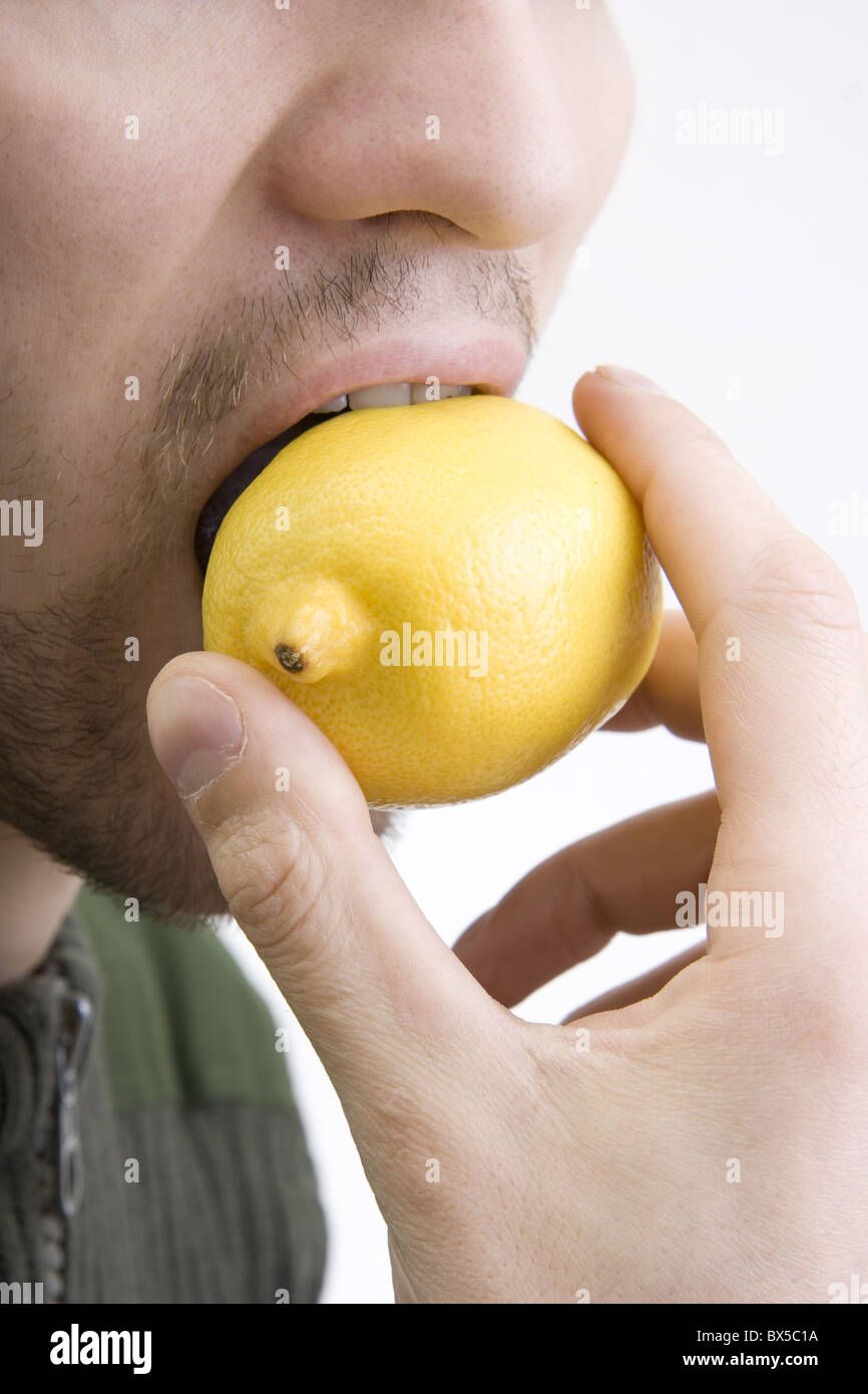 The man bites yellow lemon. Close up Stock Photo - Alamy