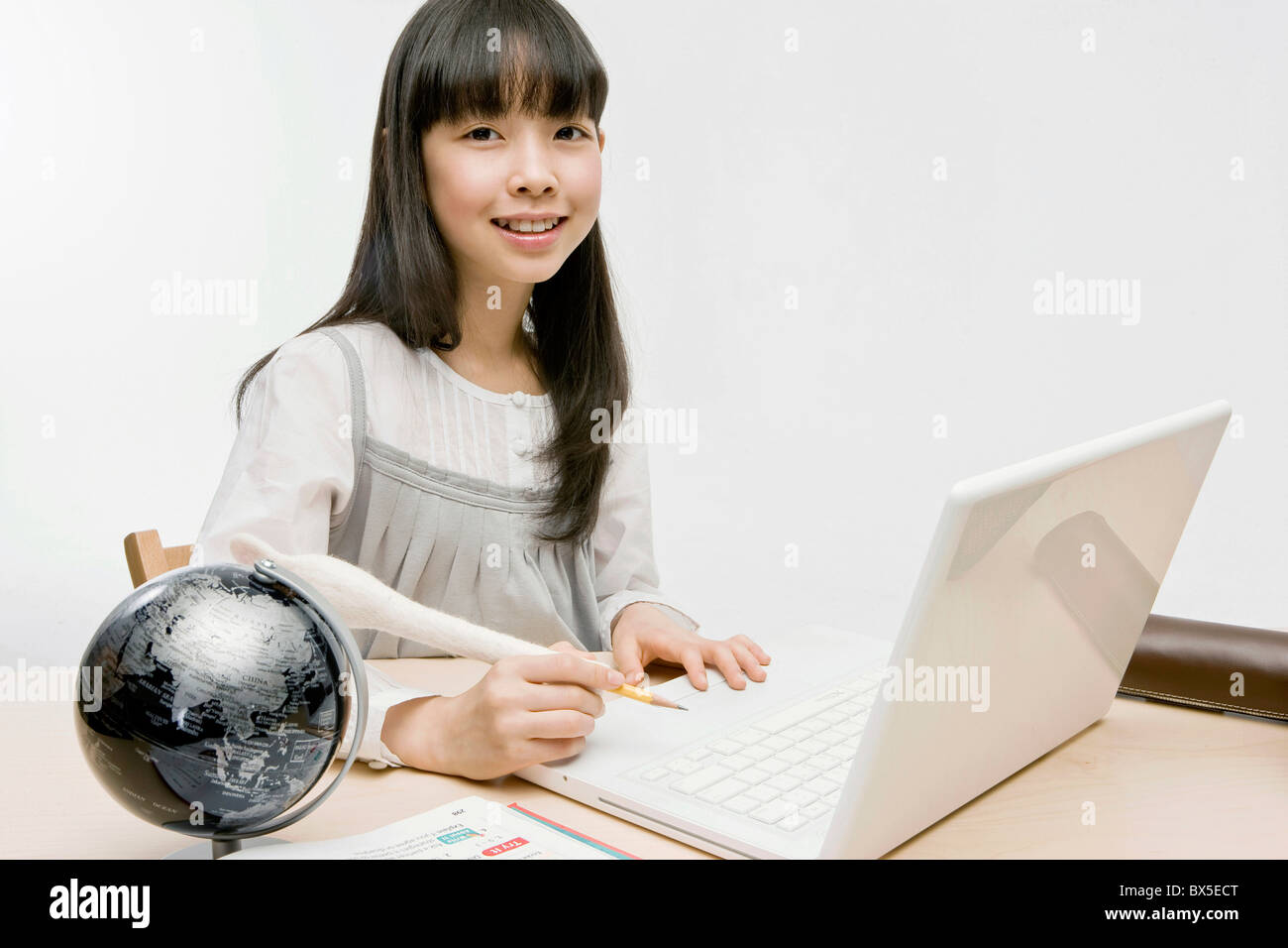 Girl sitting at desk and using laptop Stock Photo - Alamy