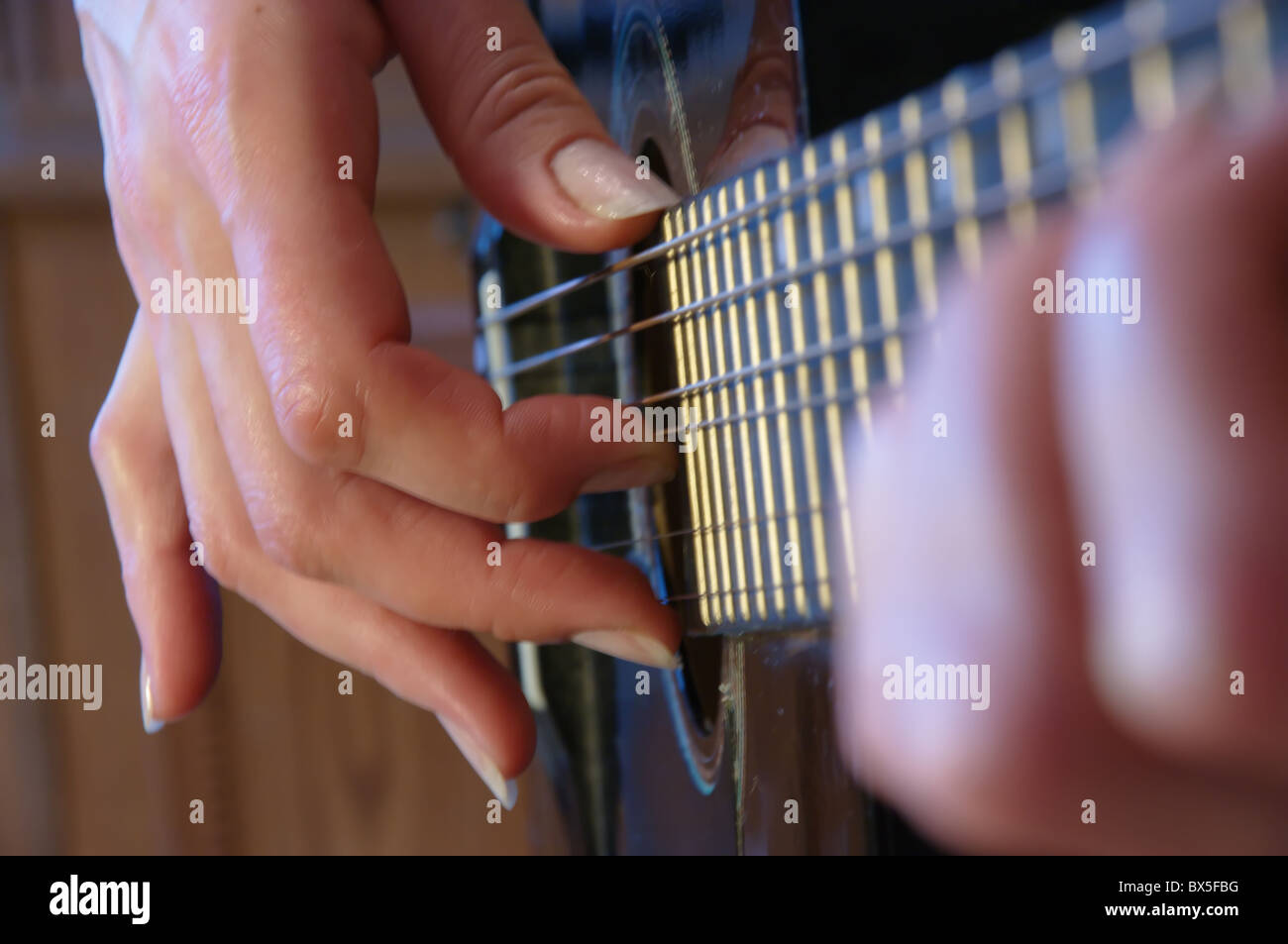 Hand touching strings on a black guitar Stock Photo - Alamy