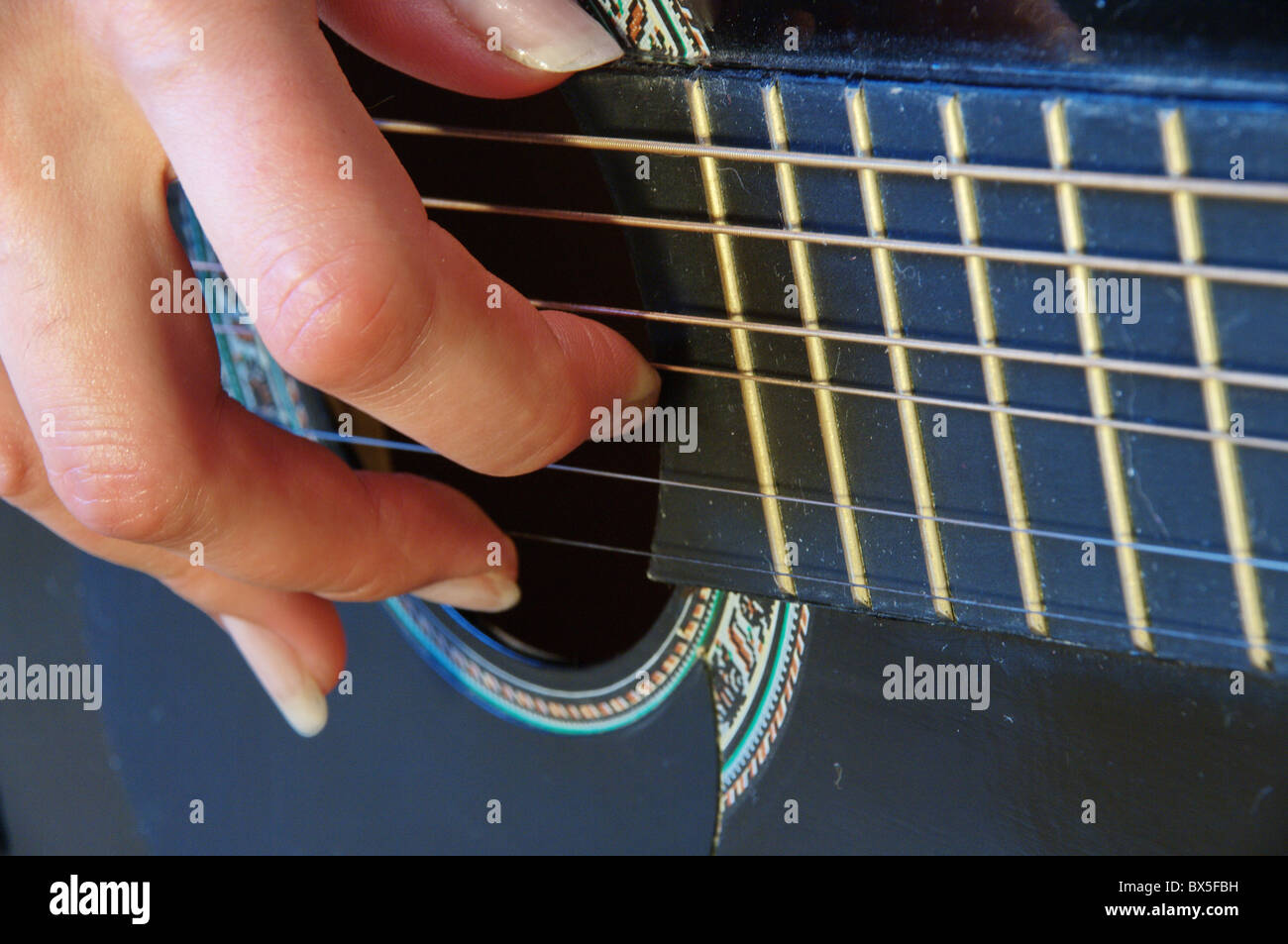 Hand touching strings on a black guitar Stock Photo - Alamy