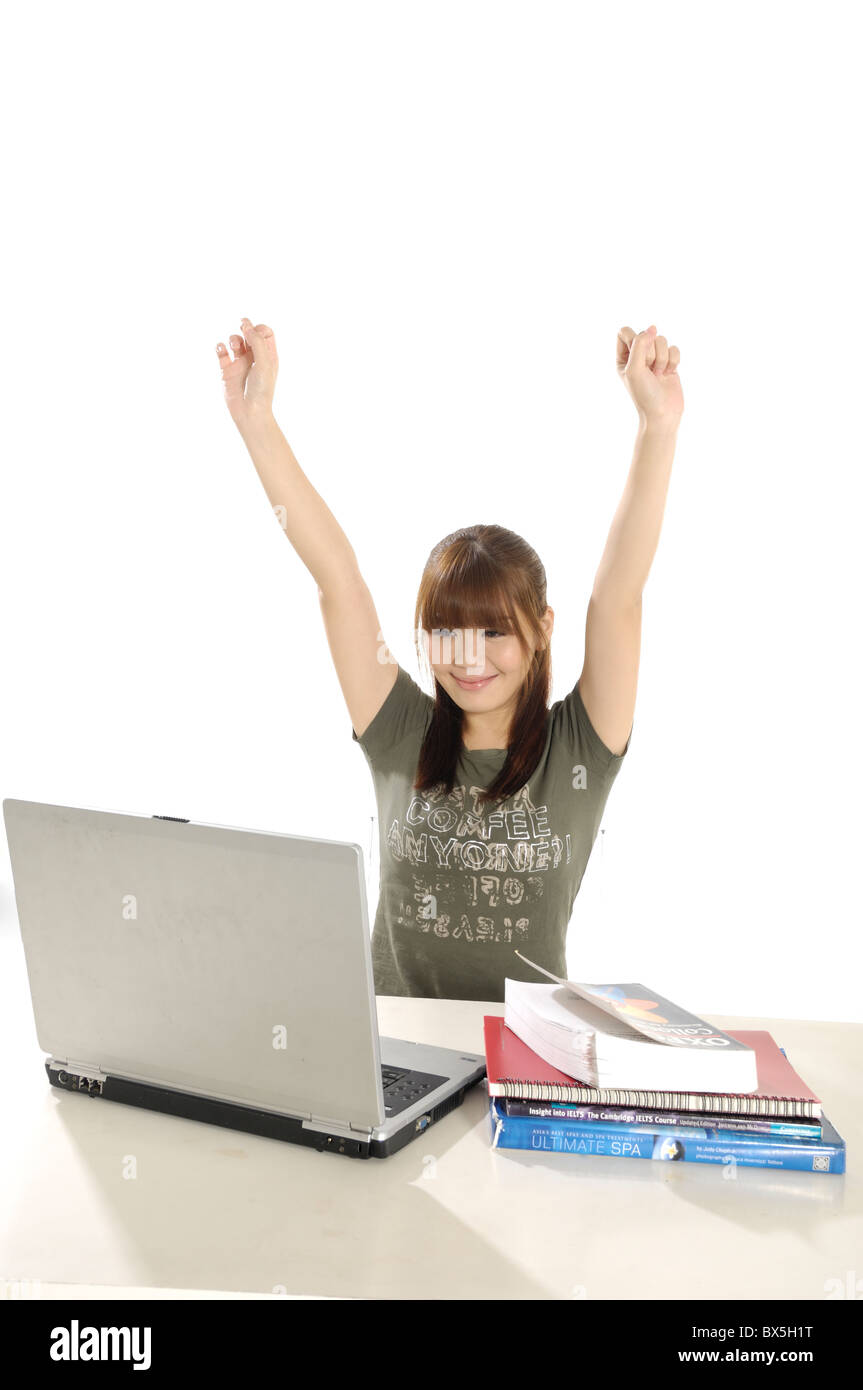 Female university student with her arms raised in front of a laptop ...